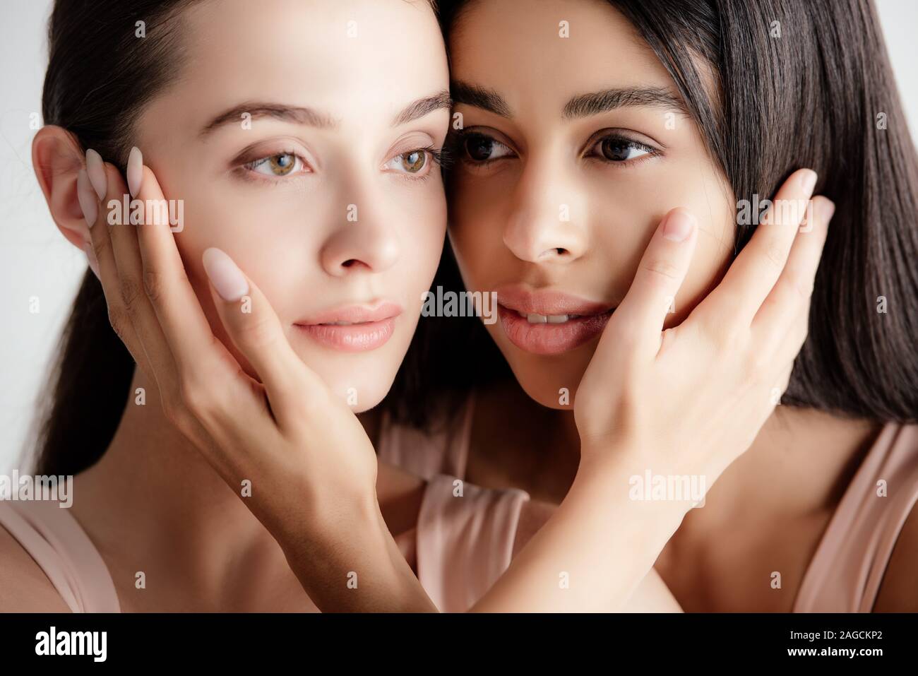beautiful young multicultural girls in beige outfit tenderly touching ...