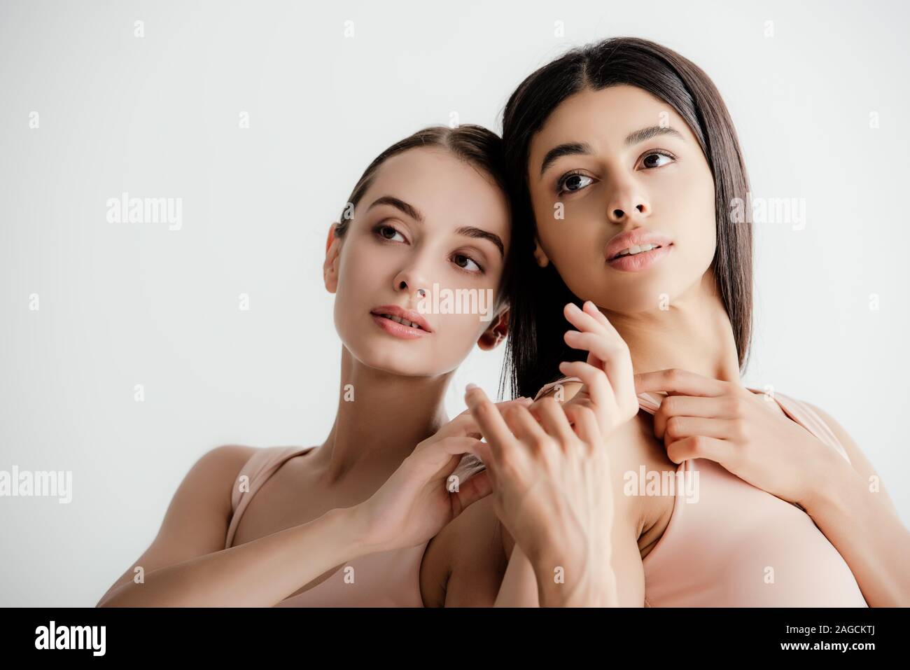 young multicultural girls in beige outfit tenderly touching each other ...
