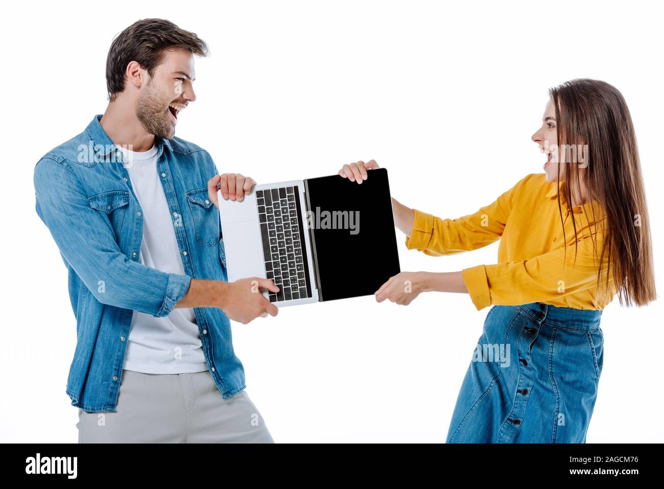 angry young couple screaming while sharing laptop isolated on white ...