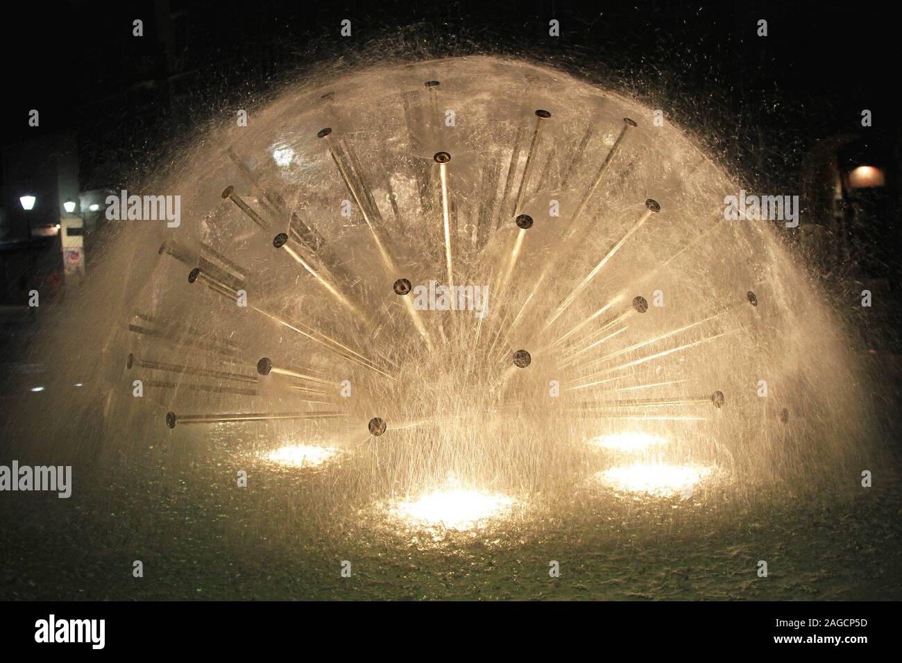Modern fountain spraying water at night Stock Photo - Alamy