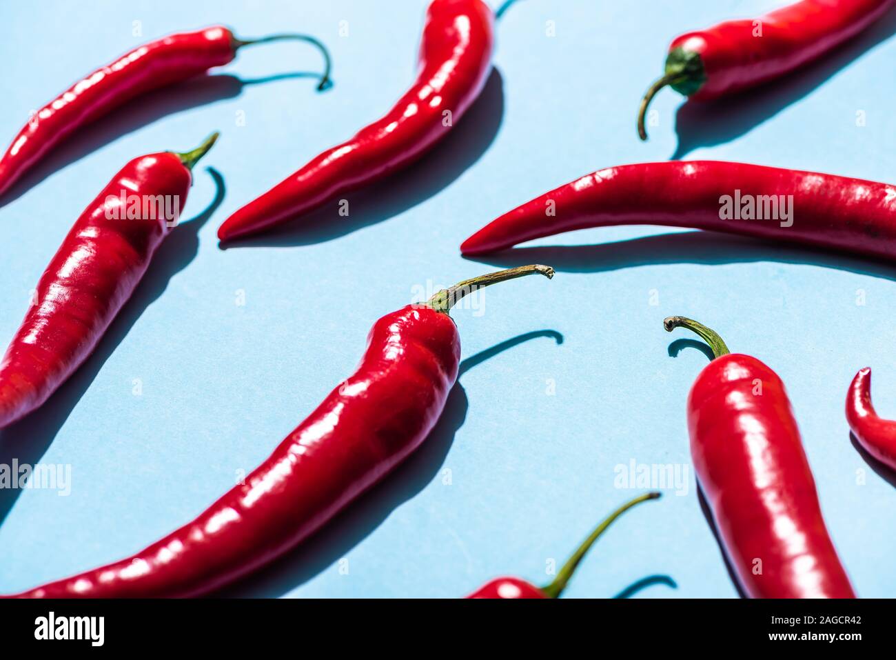 Spicy chili peppers with shadow on blue background Stock Photo - Alamy