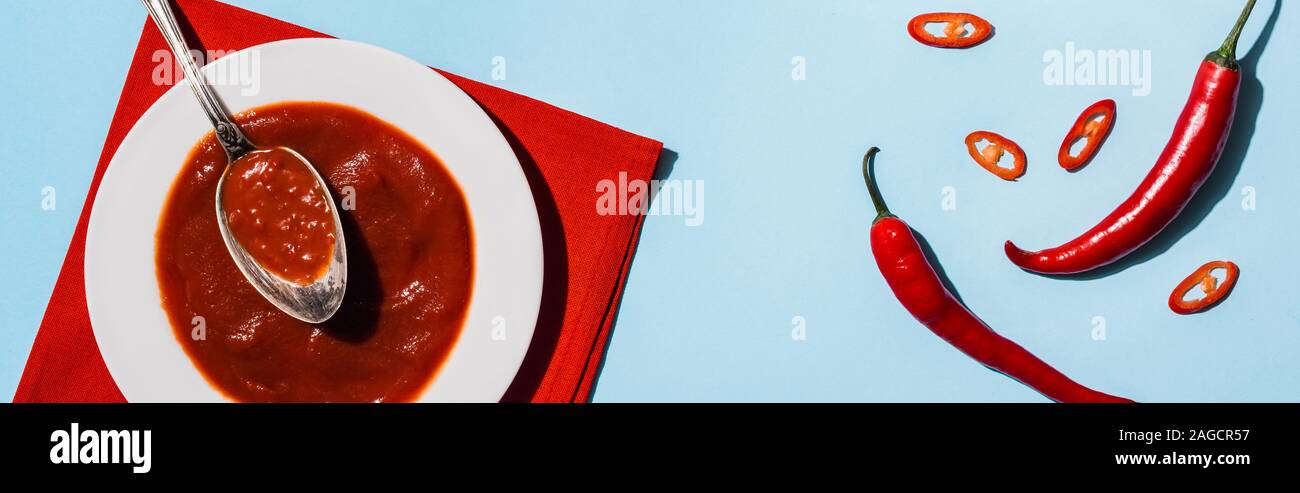 Top view of plate with spicy chili sauce and chili peppers on blue ...