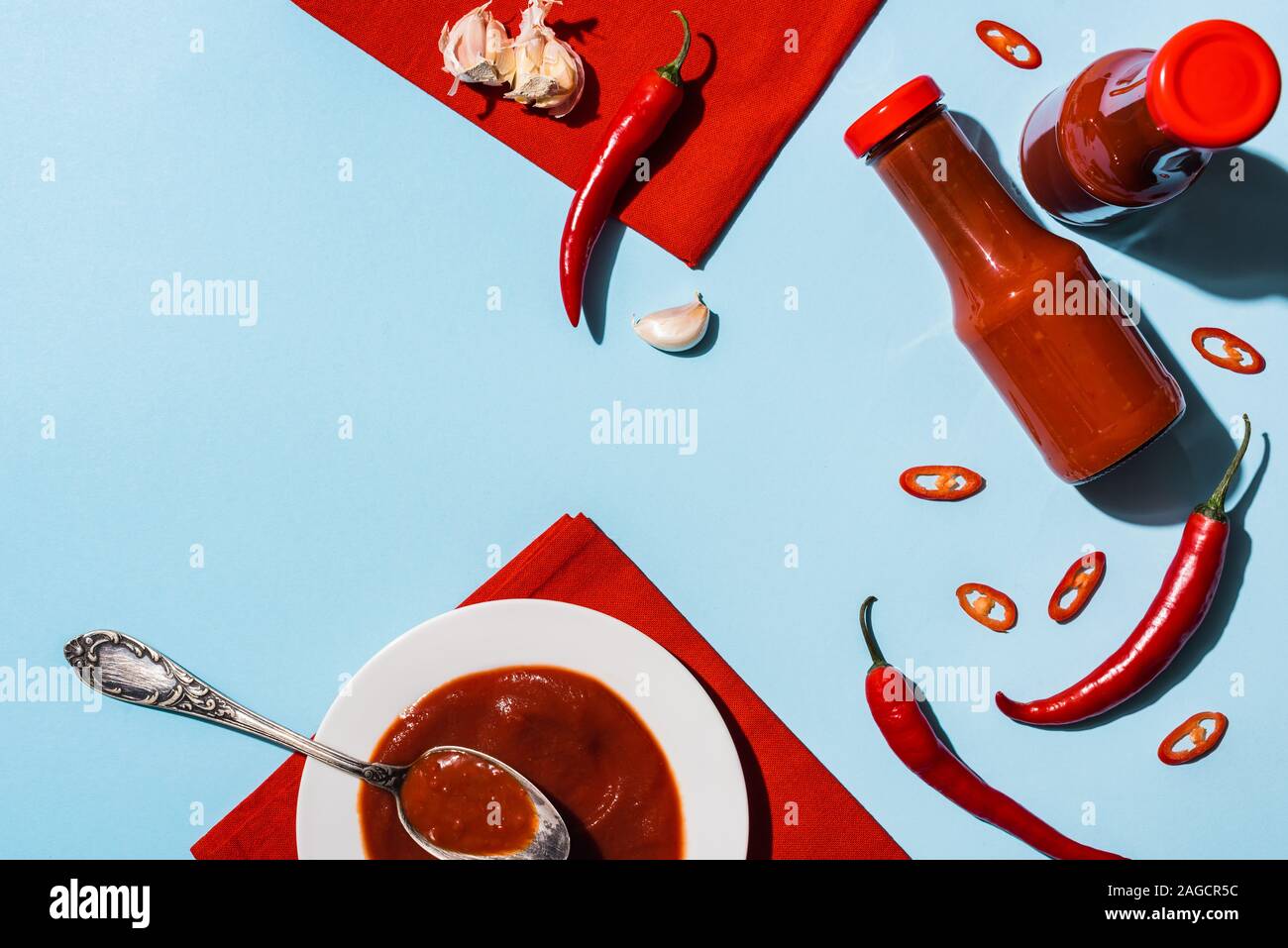 Top view of homemade chili sauce with garlic and chili pepper on blue ...