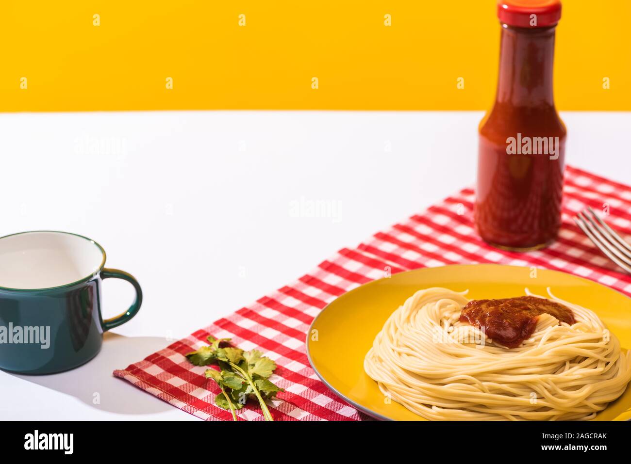 Prepared spaghetti with tomato sauce beside cup on white surface on ...