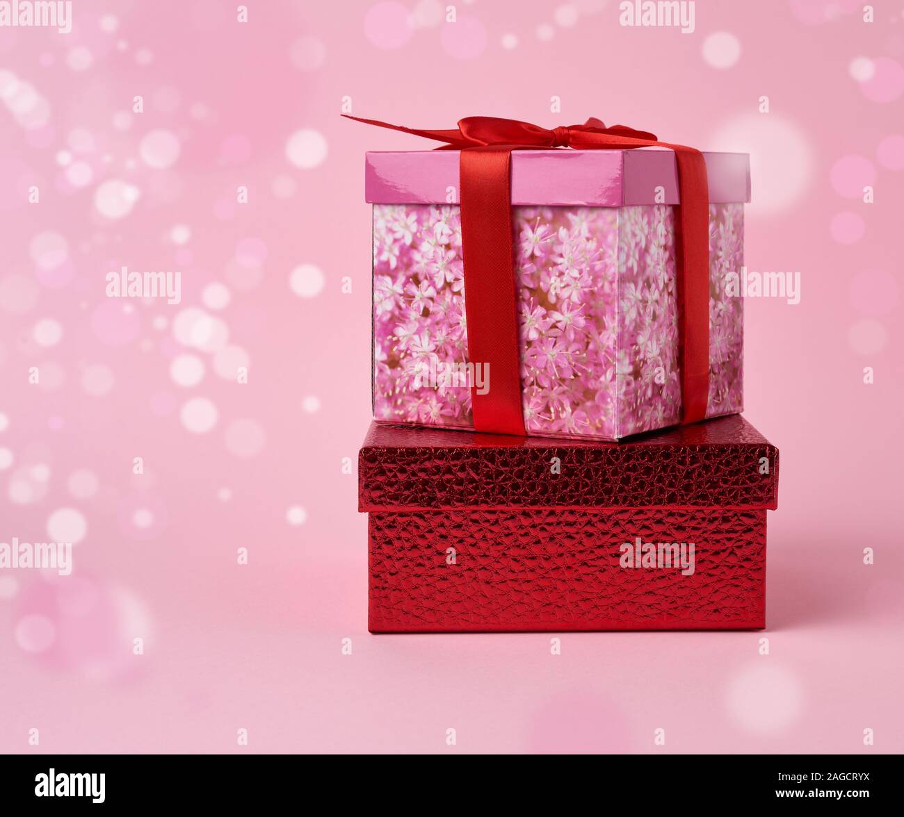stack of wrapped gifts on a pink background with bokeh. Beautiful box ...