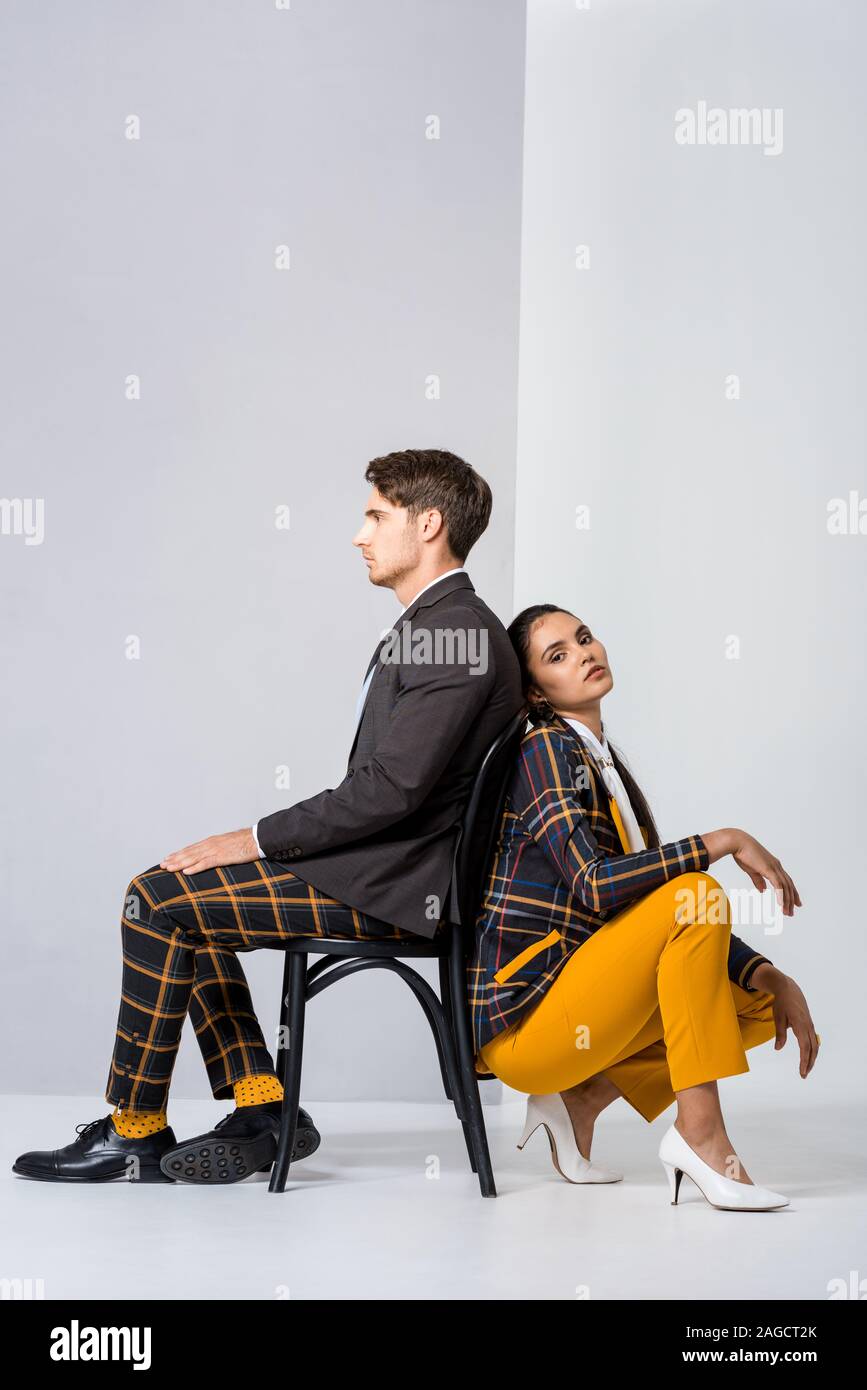 stylish woman posing near man sitting on chair on white Stock Photo - Alamy