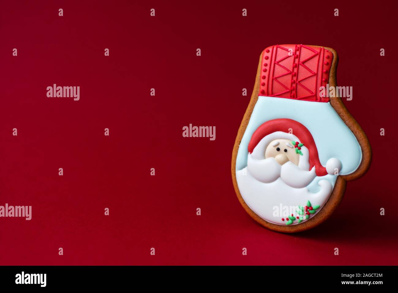 gingerbread cookie of winter glove with Santa portrait on red ...