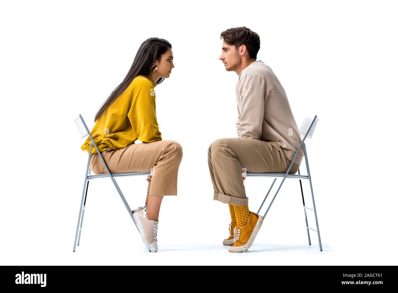 side view of attractive woman sitting on chair and looking at man on ...