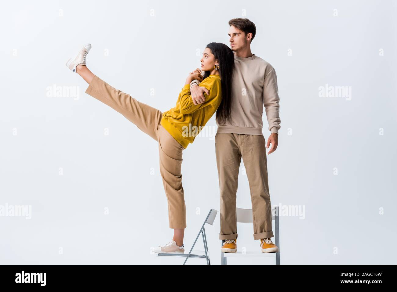 handsome man standing on chair and hugging attractive girl isolated on ...
