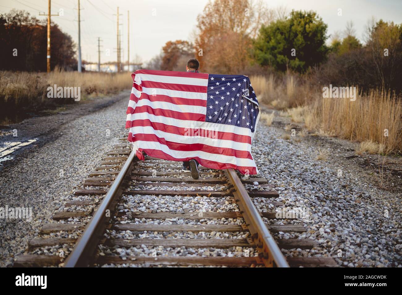 Male holding the united states flag behind him and walking on train ...