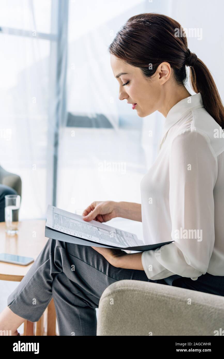 side view of attractive journalist in formal wear holding folder Stock ...