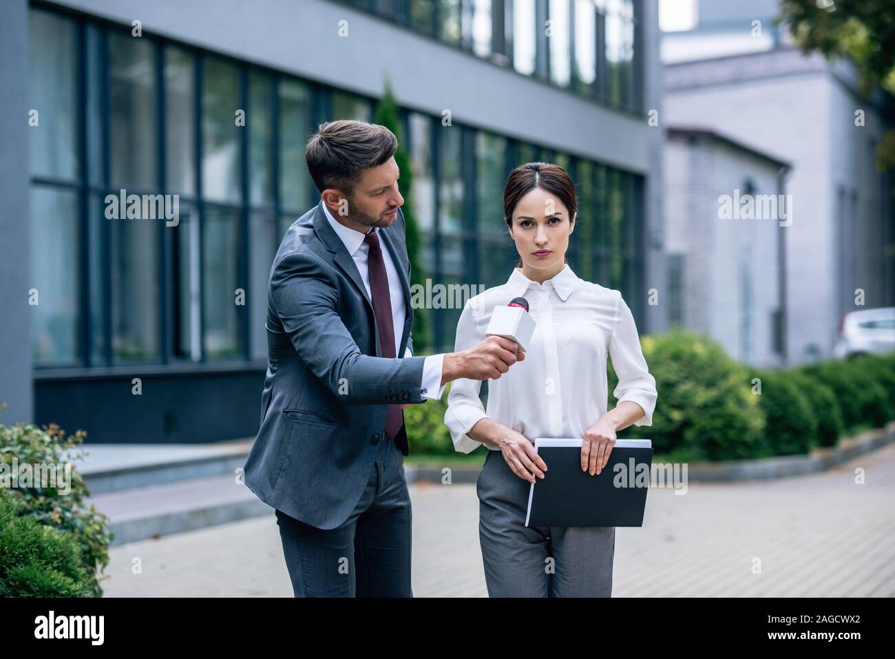journalist holding microphone and talking with businesswoman in formal ...