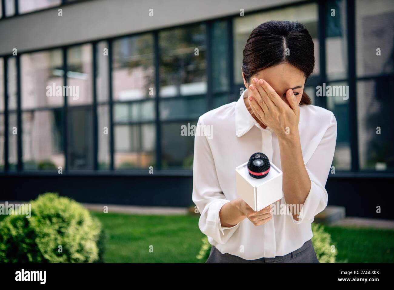 journalist in formal wear holding microphone and crying outside Stock ...