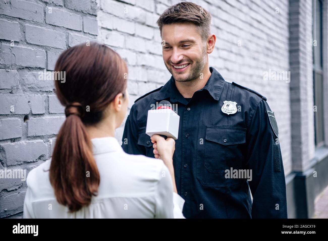 journalist holding microphone and talking with handsome policeman in ...