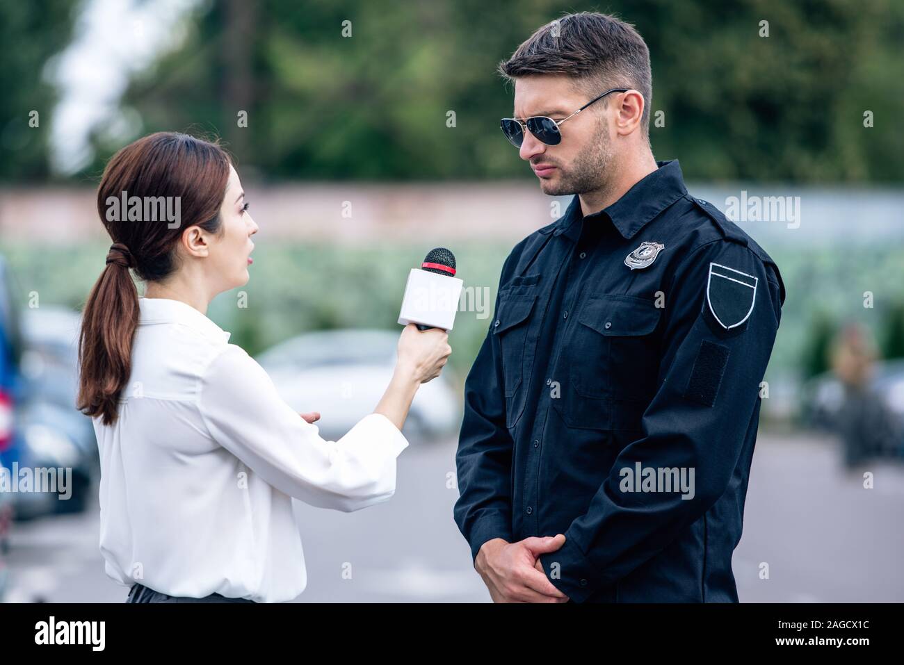 journalist holding microphone and talking with handsome policeman in ...