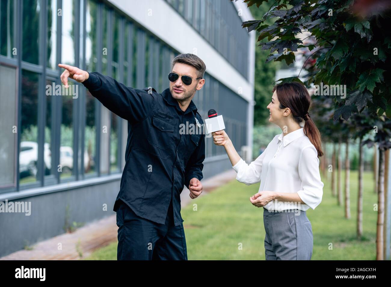 journalist holding microphone and talking with handsome policeman in ...