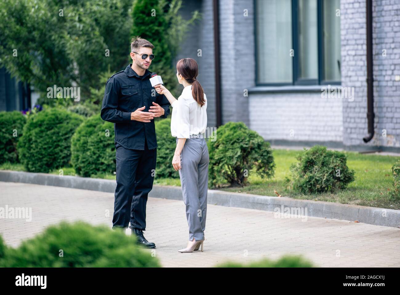 journalist holding microphone and talking with handsome policeman in ...