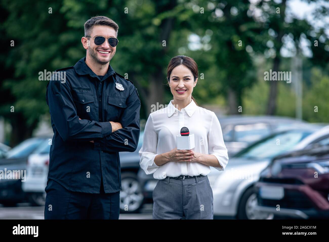 journalist holding microphone and handsome policeman in uniform looking ...