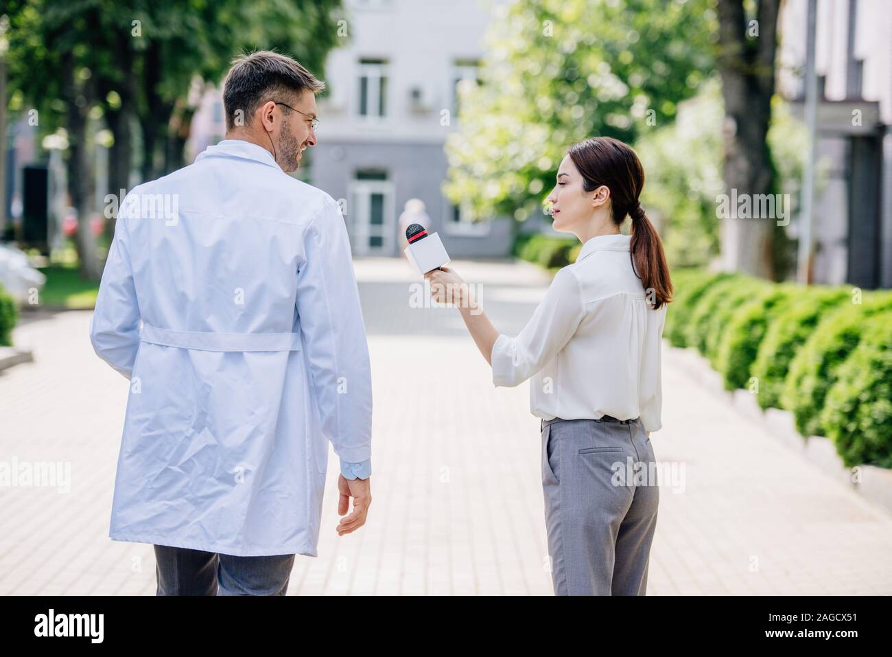 back view of journalist holding microphone and talking with doctor in ...