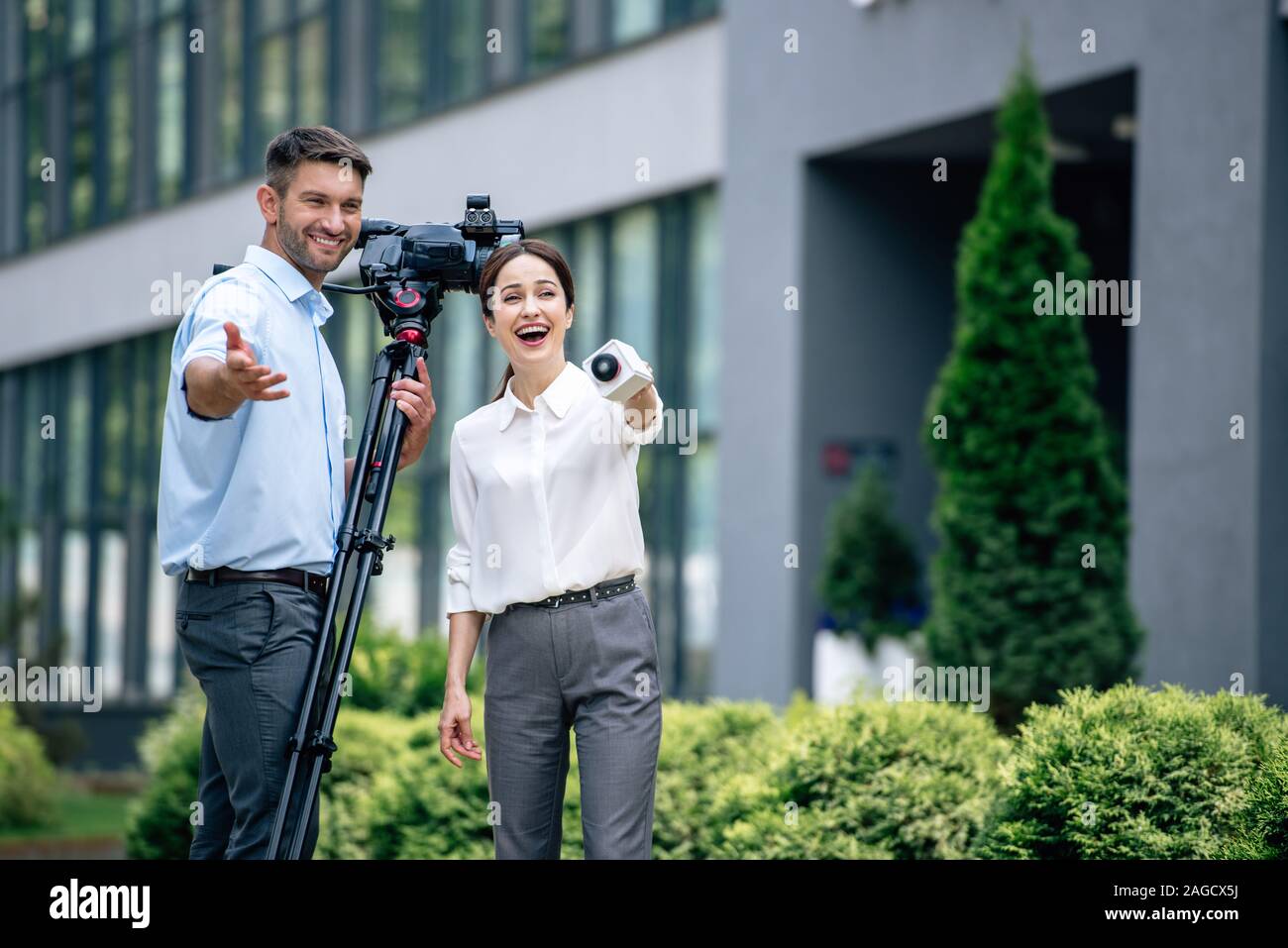attractive journalist holding microphone and cameraman holding digital ...