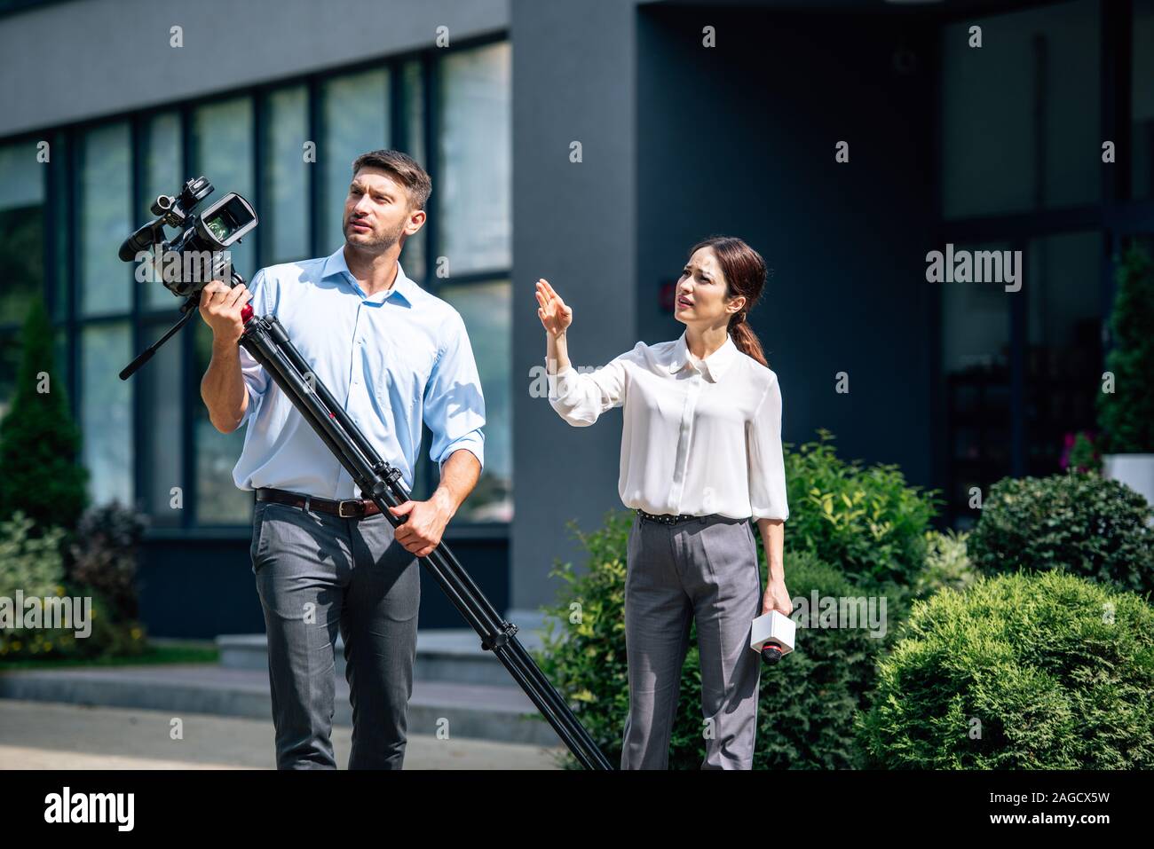 attractive journalist holding microphone and cameraman holding digital ...
