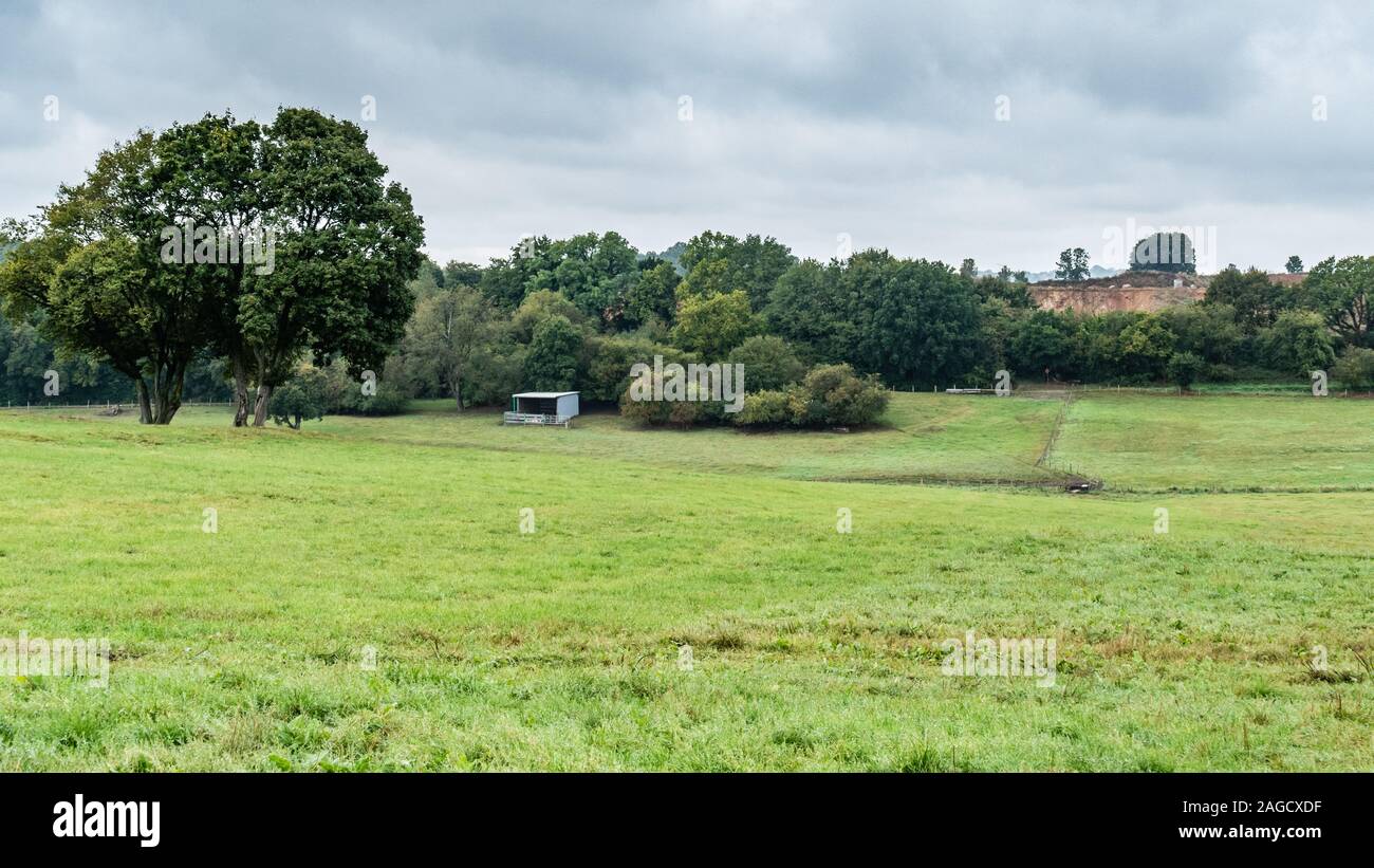 Rolling landscape with trees, animal shed of corrugated iron and cliffs ...