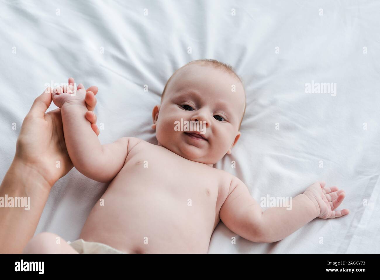 top view of mother touching hand of adorable baby daughter looking at ...