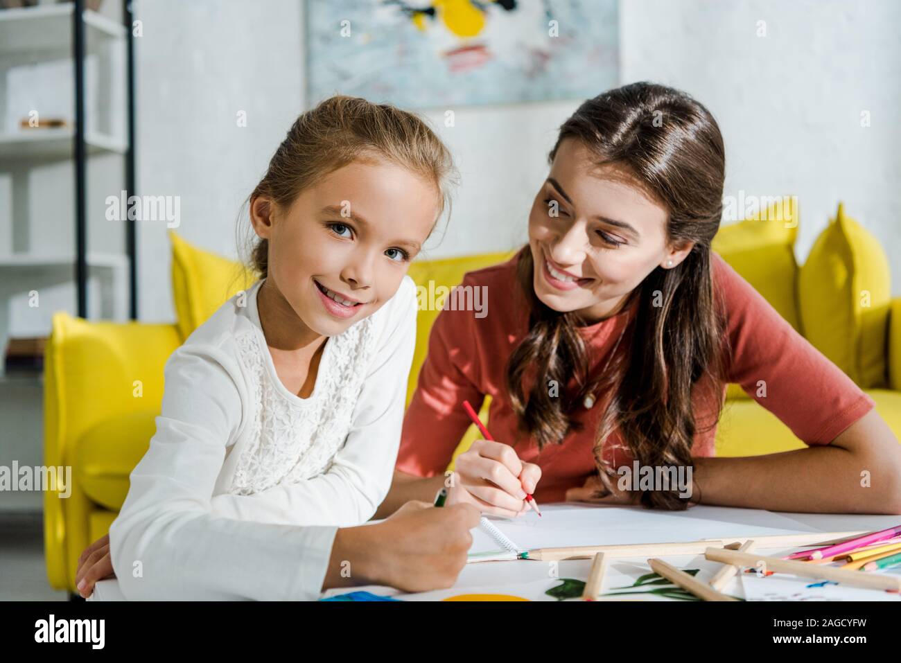 happy babysitter looking at cute kid smiling in living room Stock Photo ...