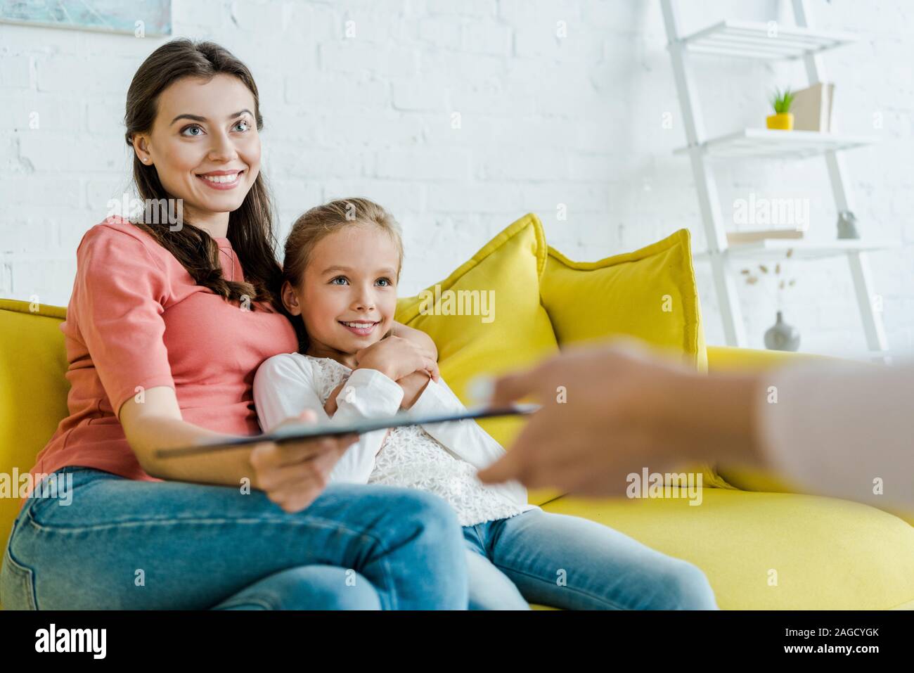 happy babysitter sitting near happy kid and mother with clipboard Stock ...
