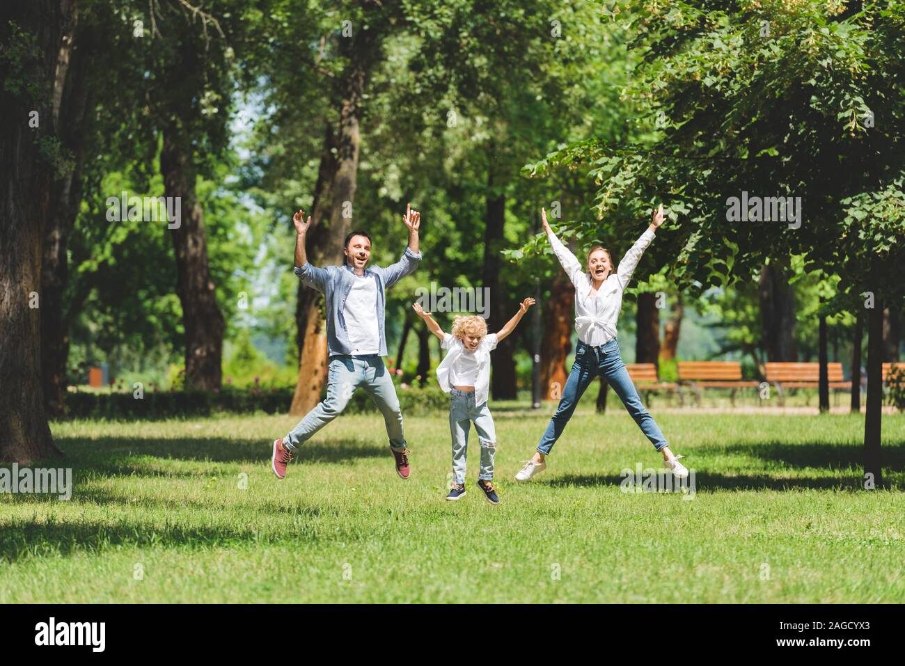 happy family jumping with raised hands in park during daytime Stock ...