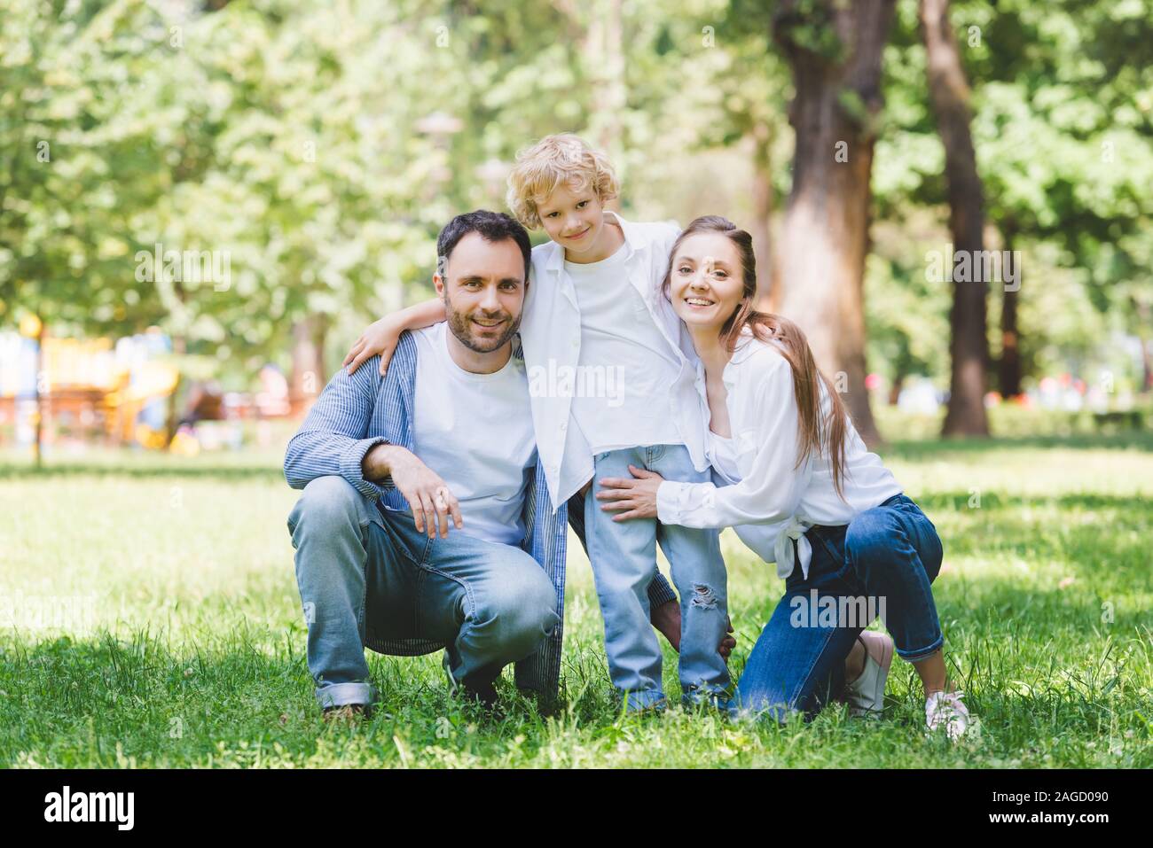happy family looking at camera and hugging in park Stock Photo - Alamy