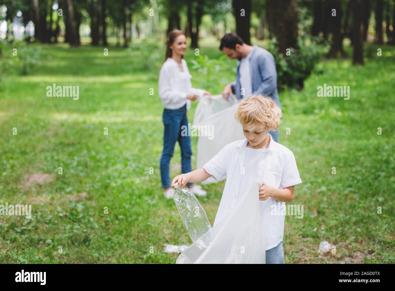 family picking up garbage in plastic bags in park with copy space Stock ...