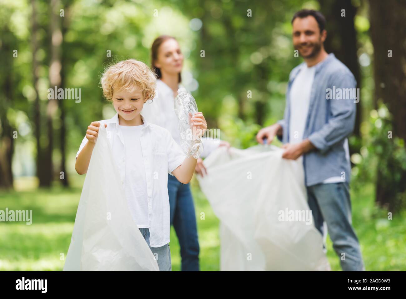 happy family picking up garbage in plastic bags in park Stock Photo - Alamy
