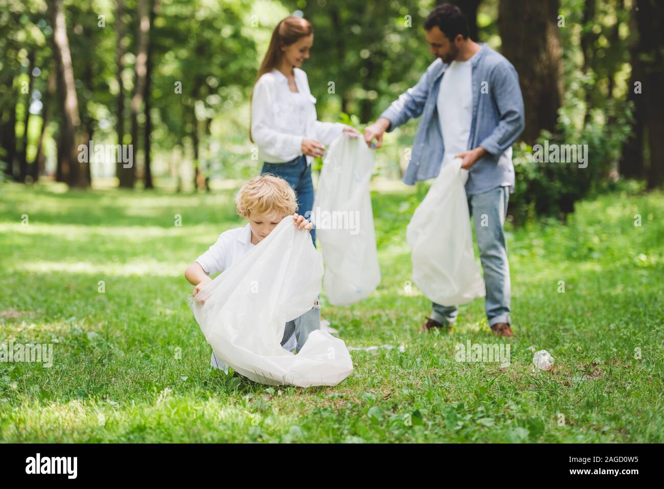 family picking up garbage in plastic bags in park Stock Photo - Alamy