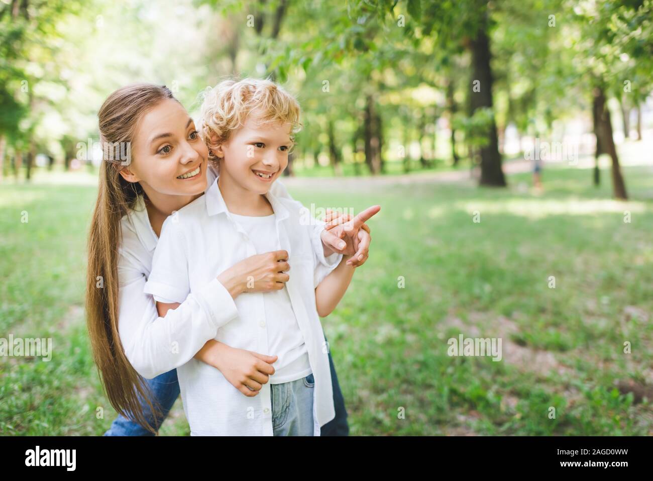 beautiful mother hugging adorable son pointing with finger at copy ...