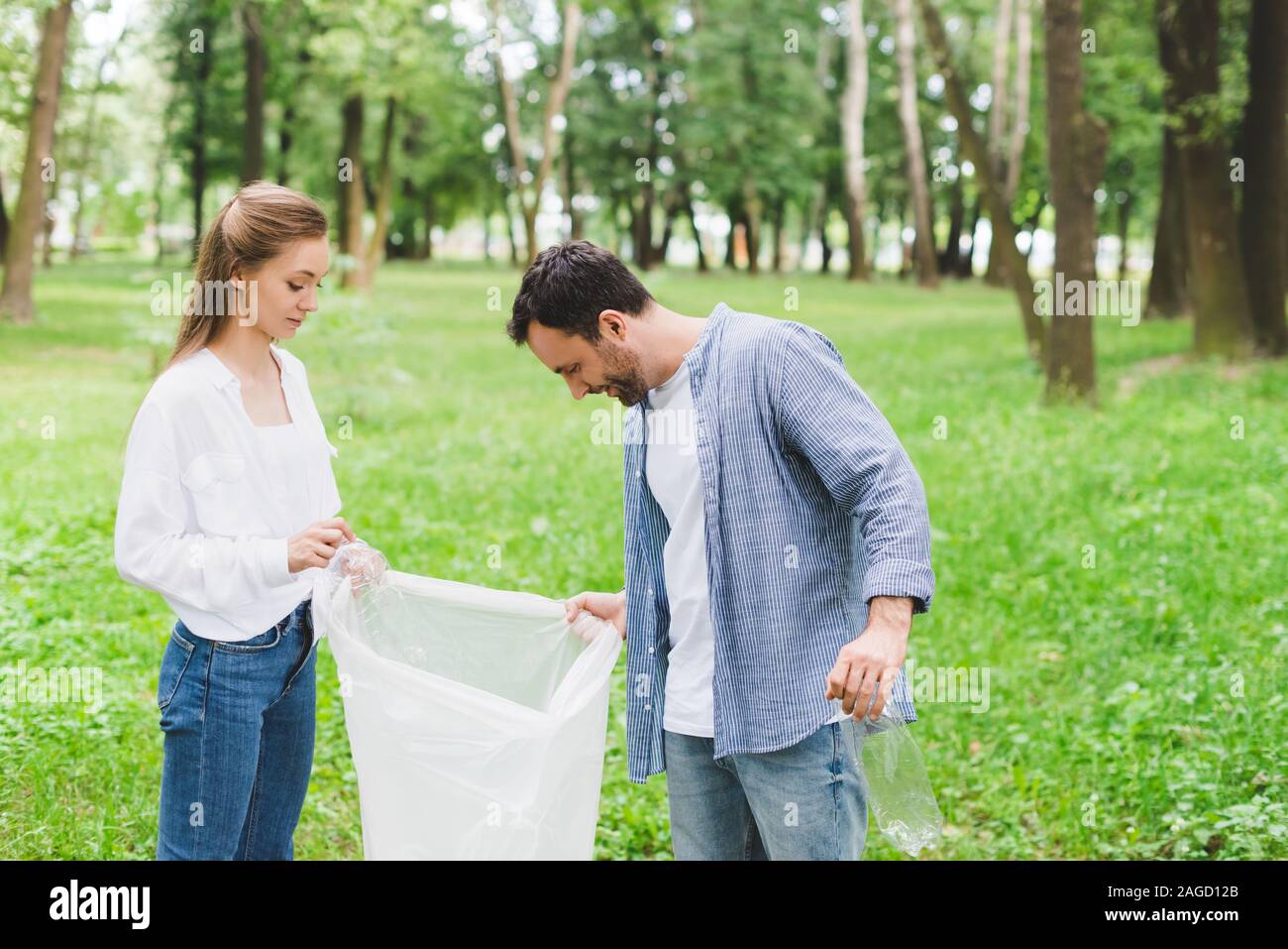 man and beautiful woman picking up garbage in plastic bag in park Stock ...
