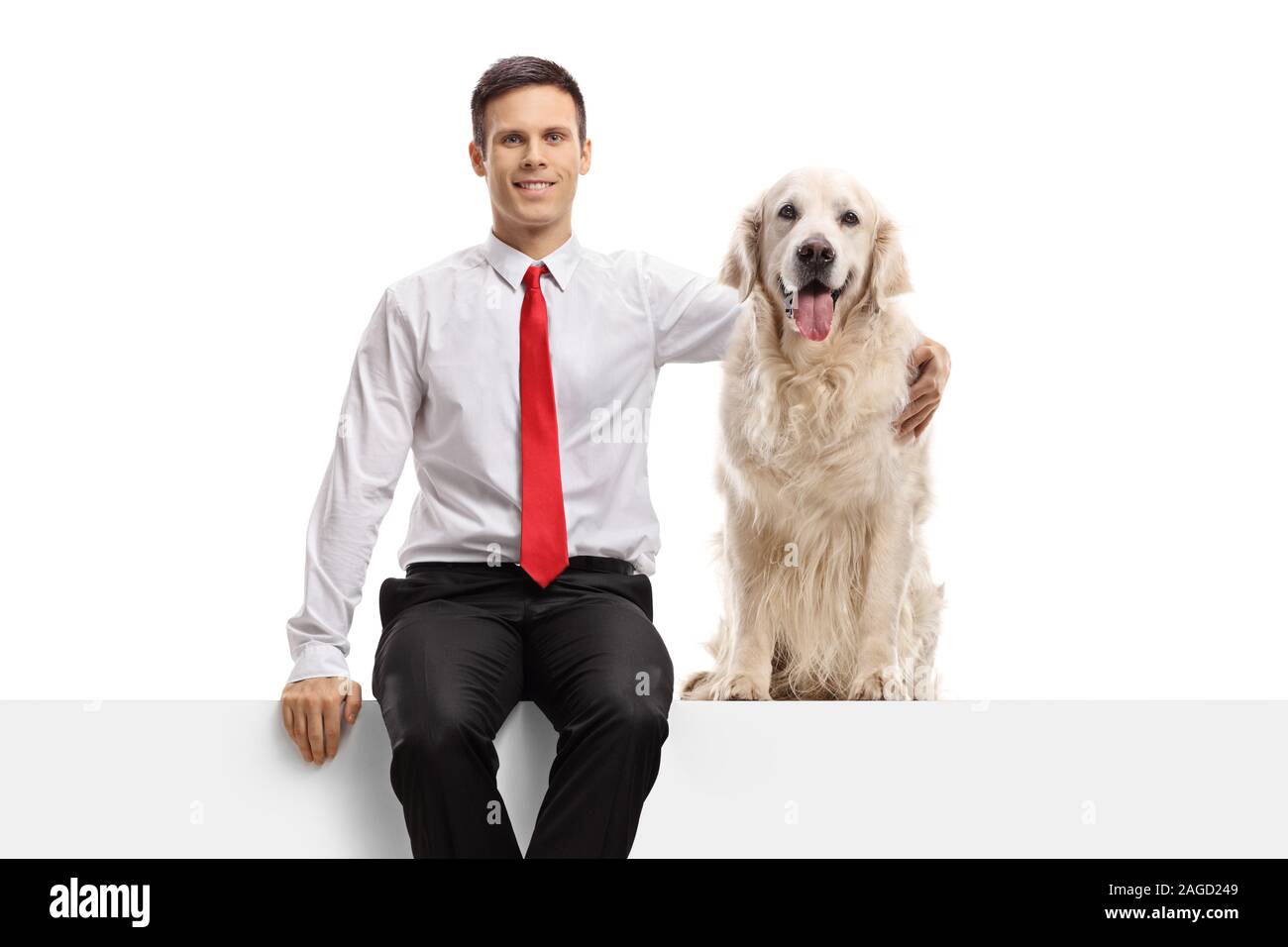 Formal young man hugging a Labrador retriever dog seated on a panel ...