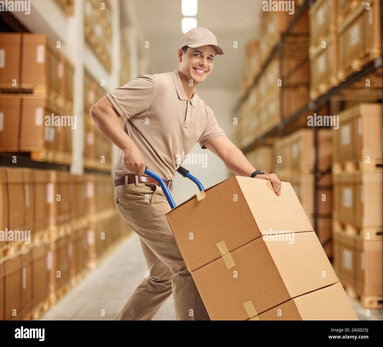 Delivery man with a hand truck loaded with boxes working in a warehouse ...