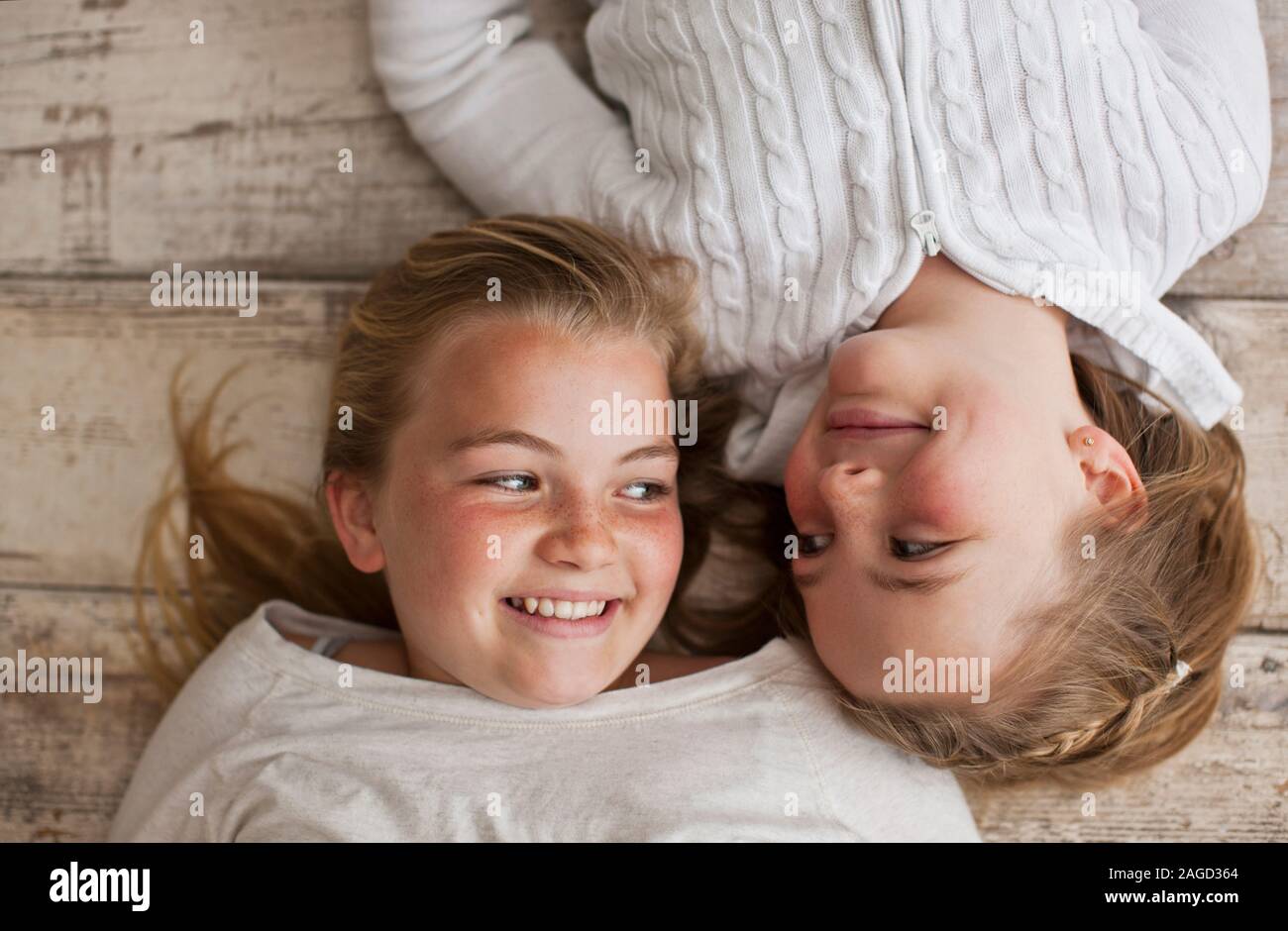 Two sisters smiling at each other while lying side by side on a ...