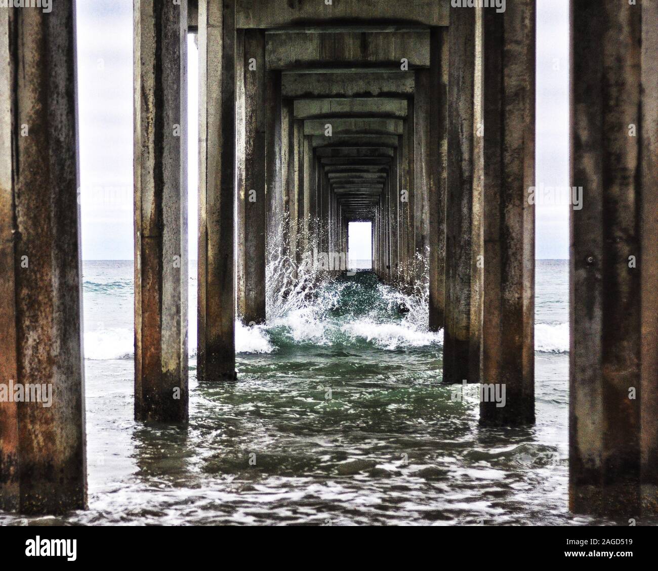 Low angle shot of ocean waves splashing to the bridge columns Stock ...