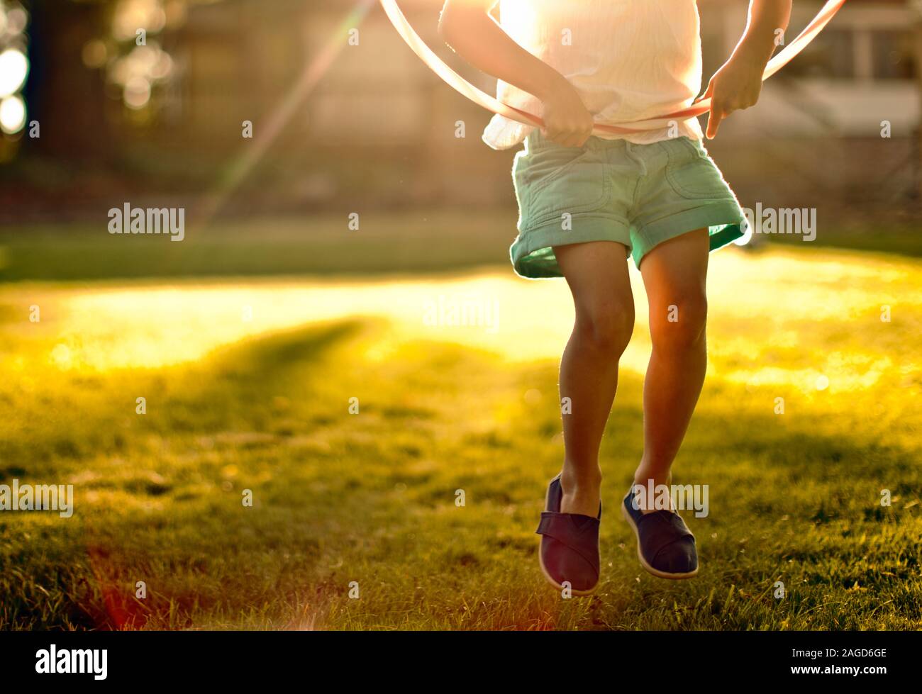 Young girl jumping through a hula hoop Stock Photo - Alamy