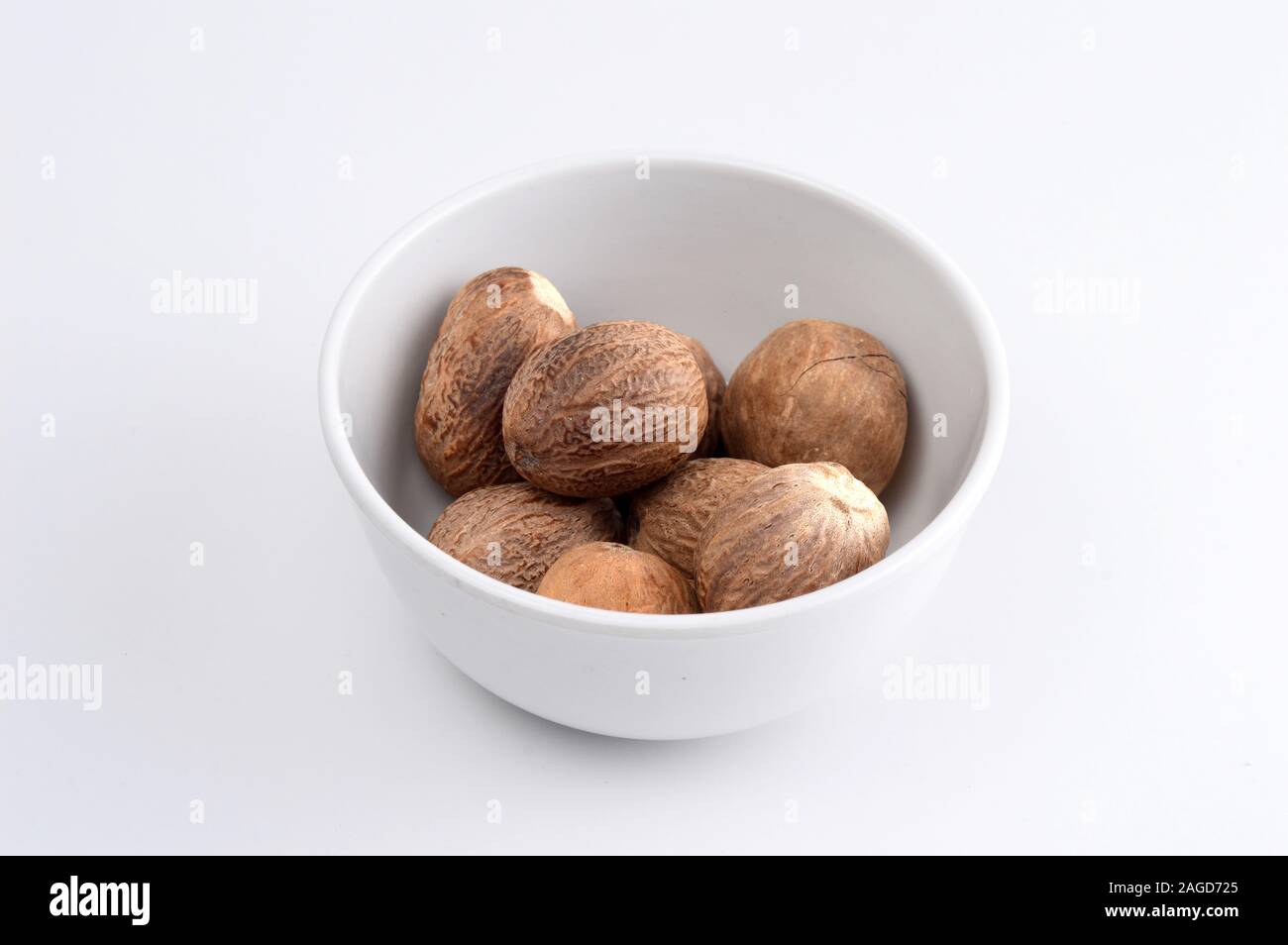 Nutmeg in white plate isolated on white background Stock Photo - Alamy