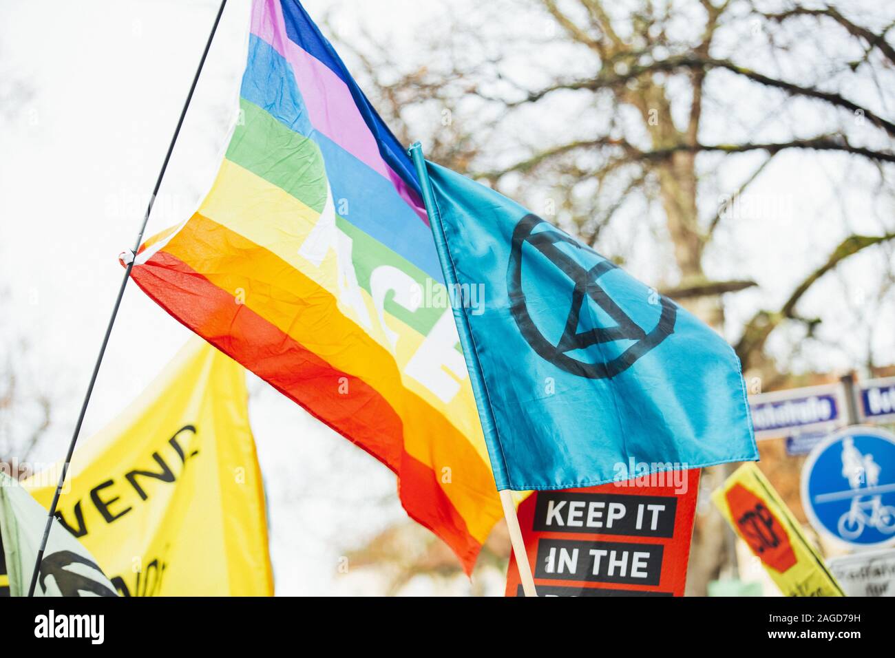 Closeup of a pride flag during a parade surrounded by trees with a ...