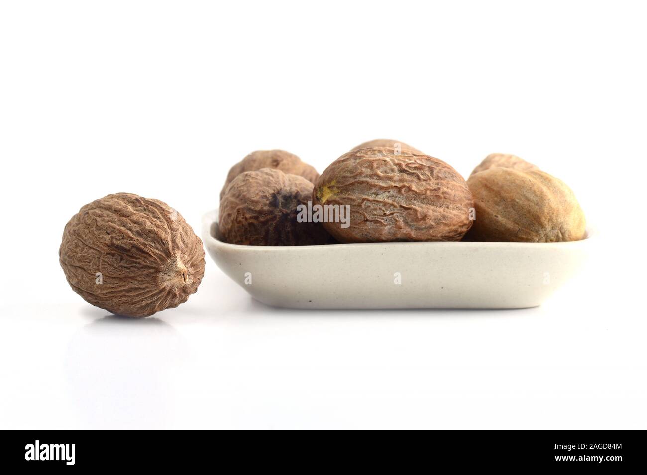 Nutmeg in white plate isolated on white background Stock Photo - Alamy