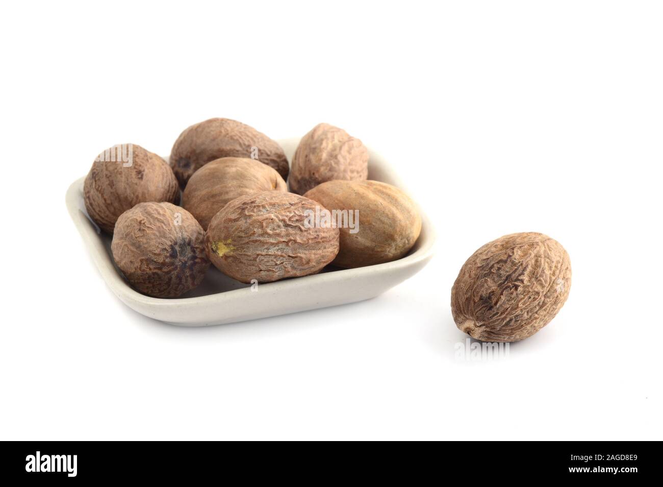 Nutmeg in white plate isolated on white background Stock Photo - Alamy