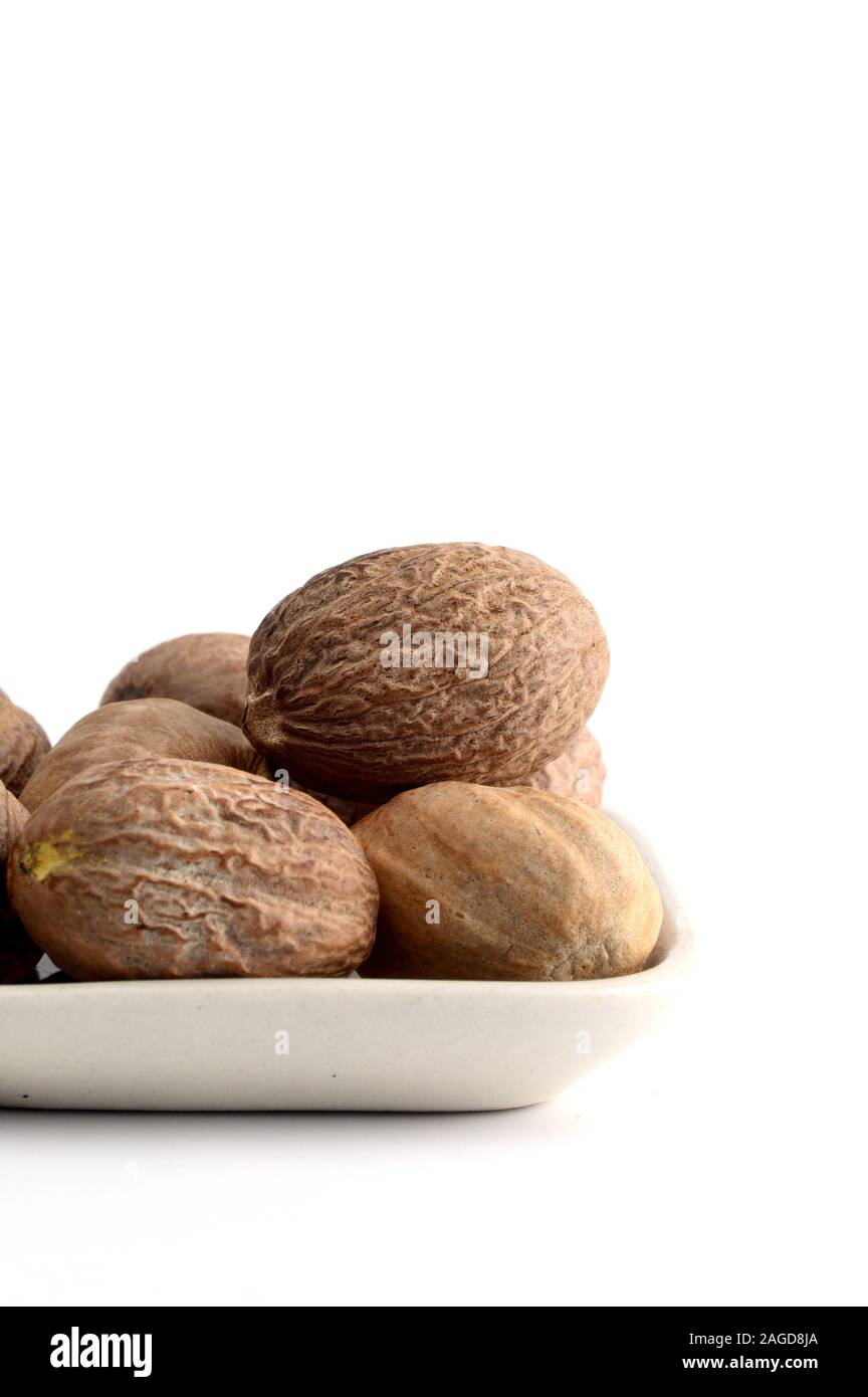 Nutmeg in white plate isolated on white background Stock Photo - Alamy