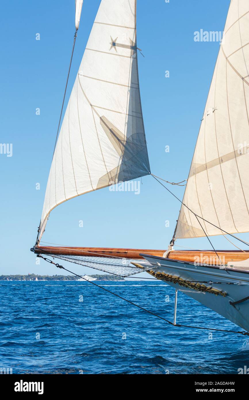 Vertical shot of a schooner bow with white sails on the sea during ...