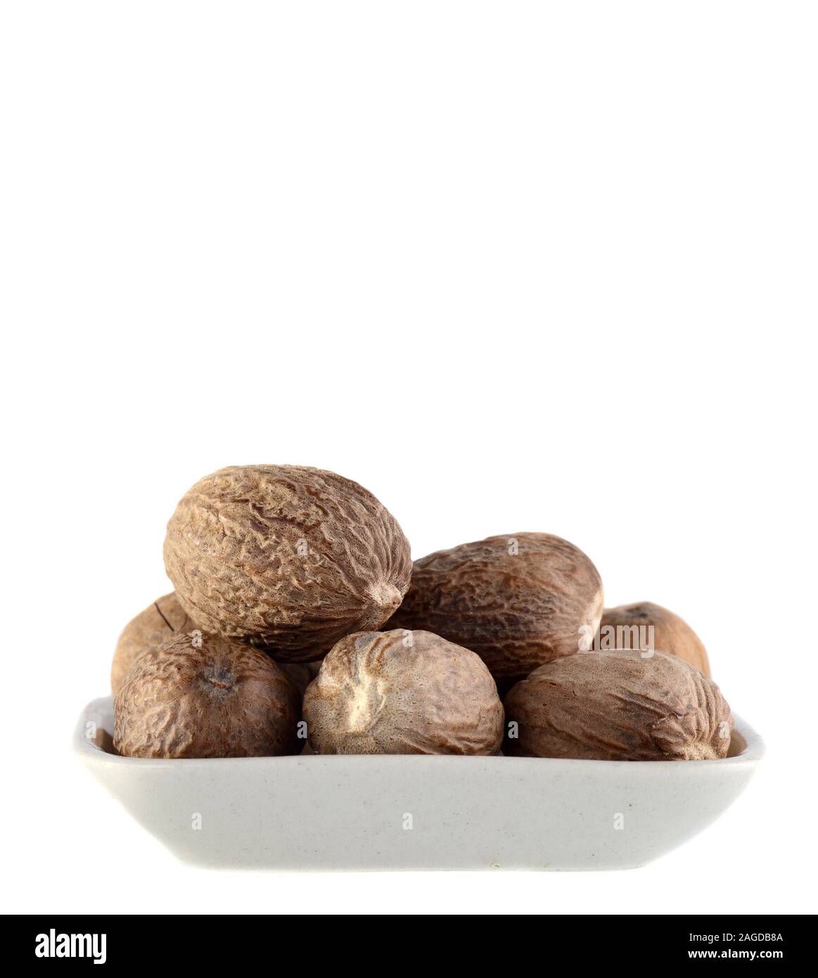 Nutmeg in white plate isolated on white background Stock Photo - Alamy