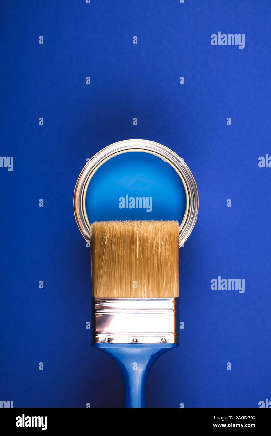 Brush on open can of blue paint on blue background. Color of the year ...