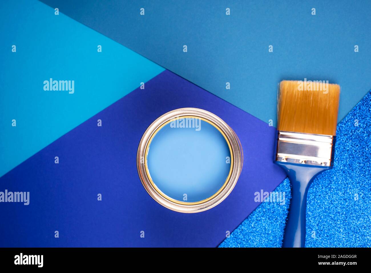 Brush on open can of blue paint on blue background. Color of the year ...